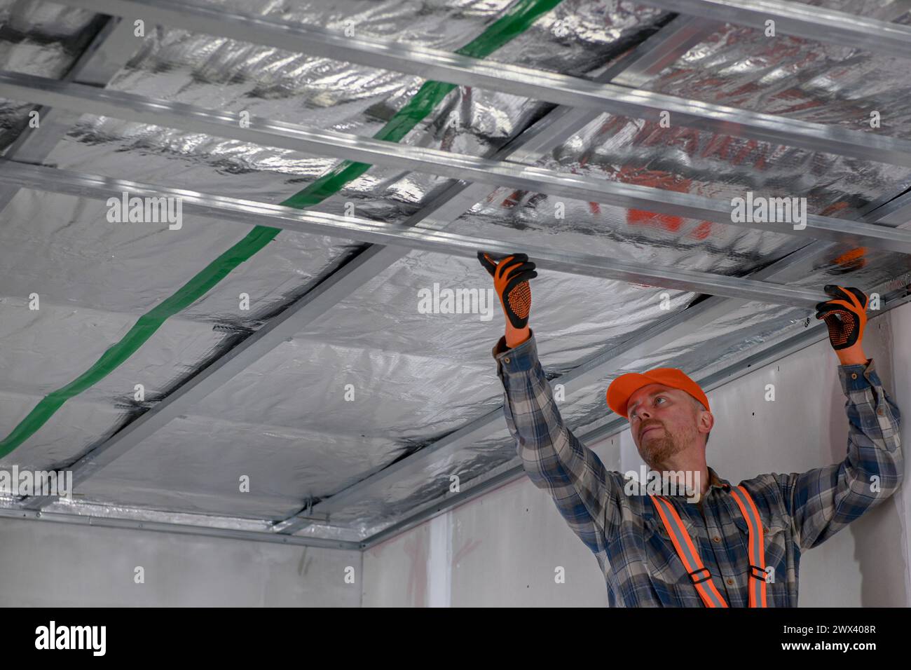 construction worker in overalls, gloves and tool belt assembles iron ...