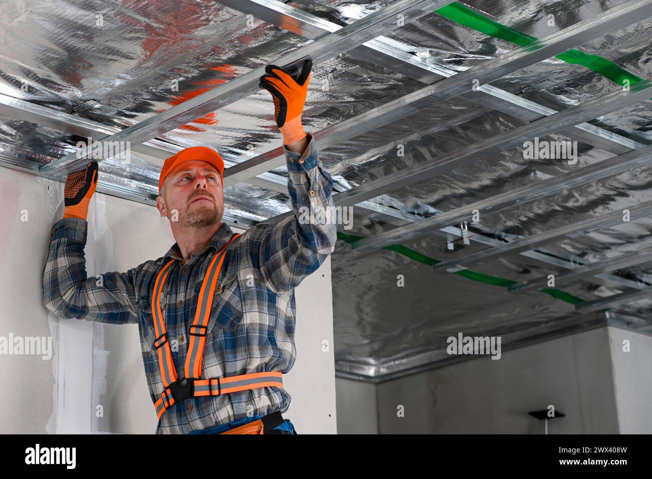 construction worker in overalls, gloves and tool belt assembles iron ...