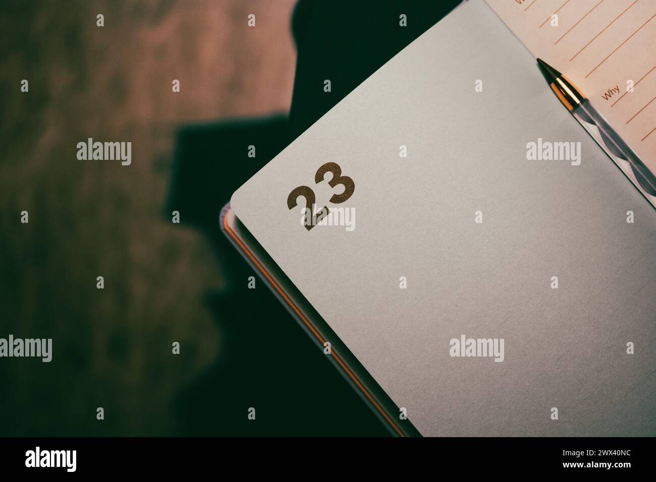 An open pad with a date 23 is lying on dark table top view. A notebook ...