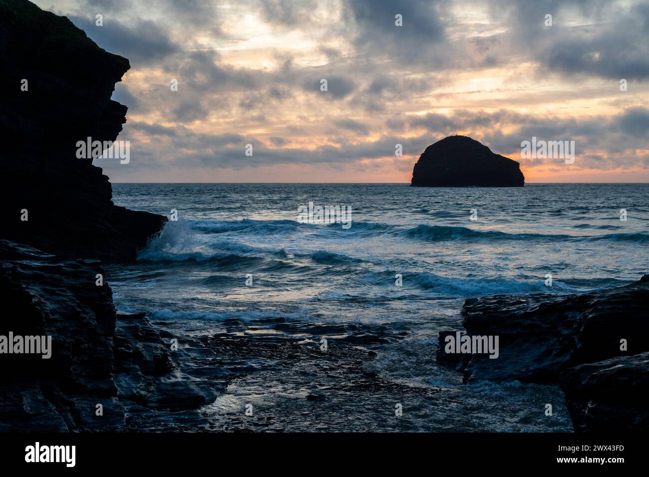 The sun setting behind Gull Rock viewed from Trebarwith Strand Beach ...