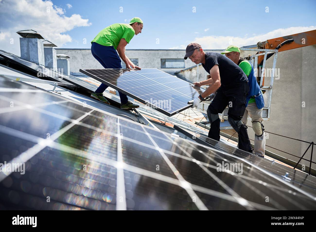 Workers building solar panel system on metal rooftop of house with ...