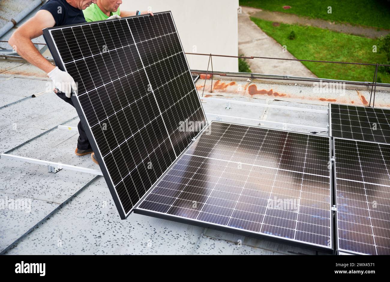 Workers building solar panel system on metal rooftop of house. Two men ...