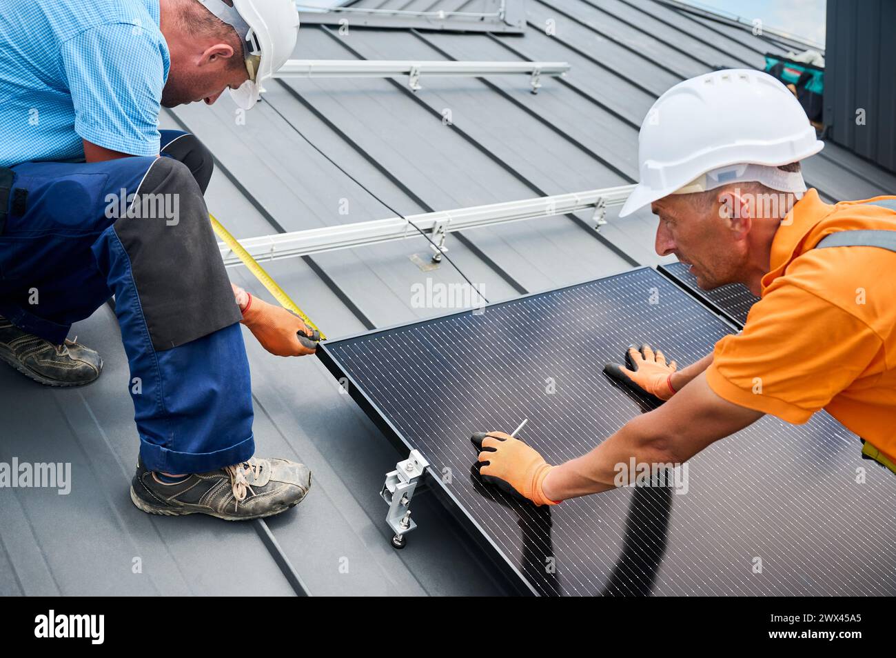 Workers building solar panel system on rooftop of house for generating ...