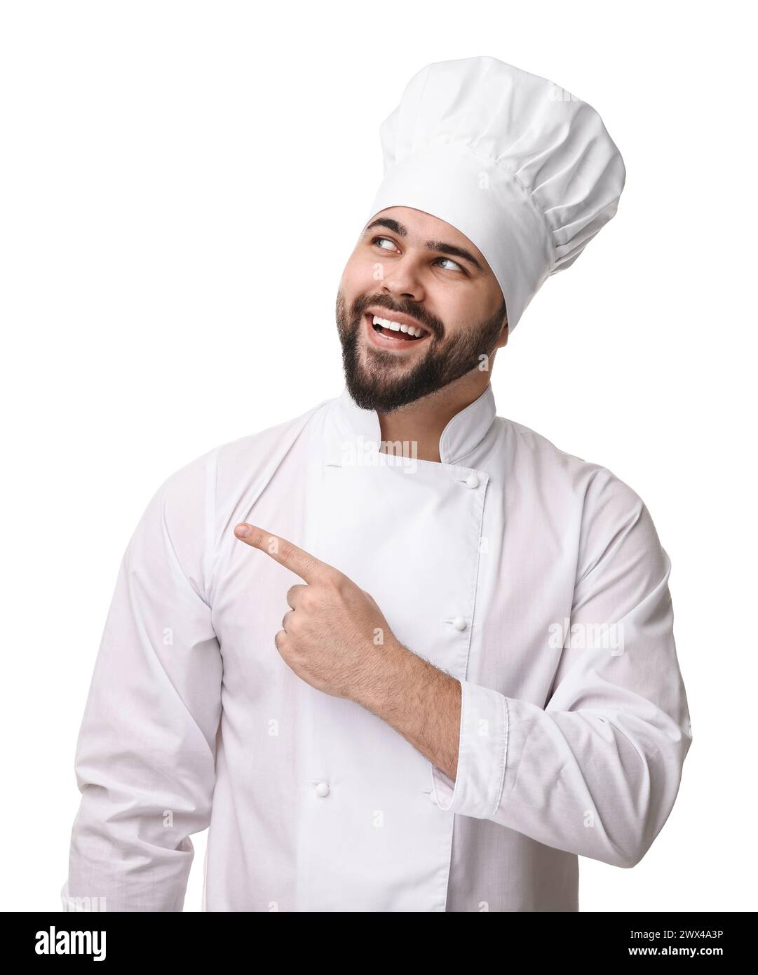 Happy young chef in uniform pointing at something on white background ...