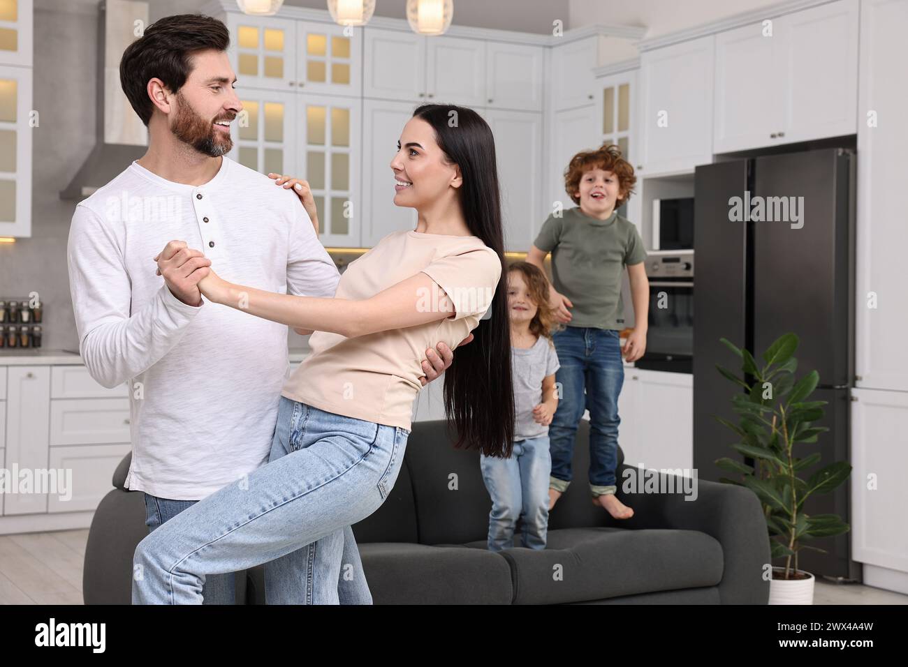 Happy family having fun at home. Couple dancing while children jumping ...