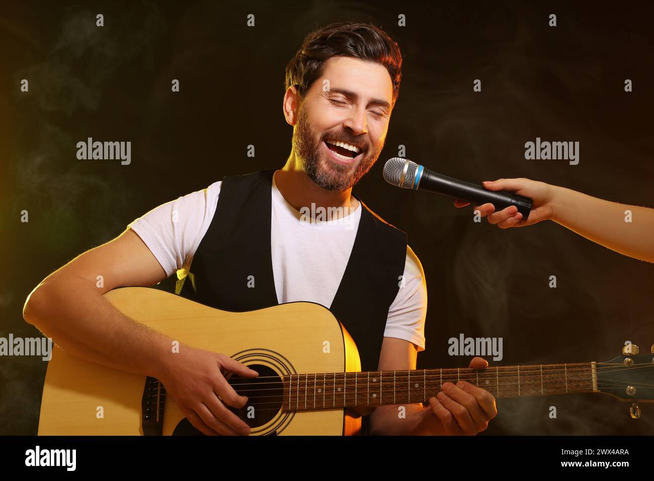 Handsome man with acoustic guitar singing while woman holding ...