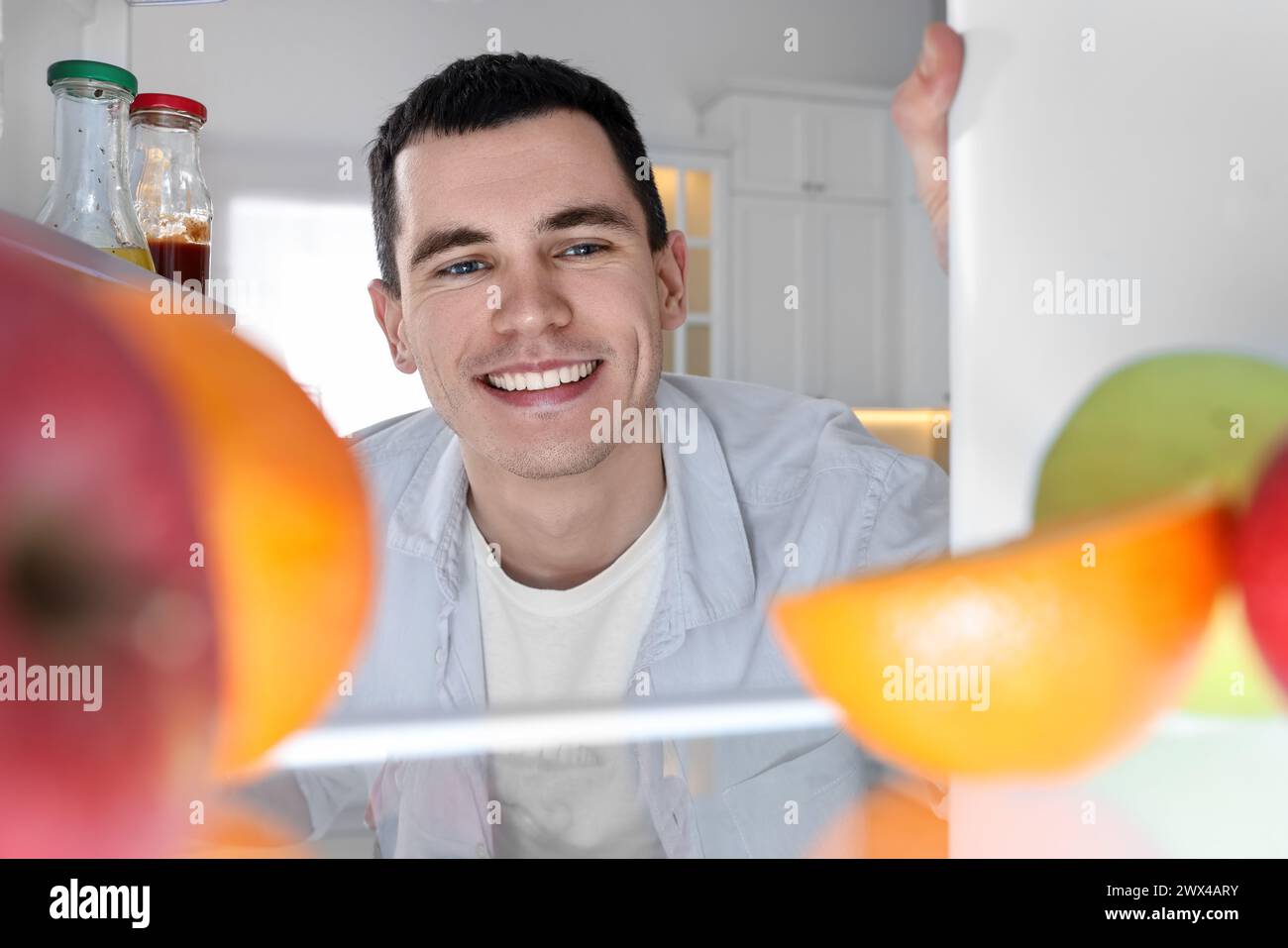 Happy man near refrigerator in kitchen, view from inside Stock Photo ...
