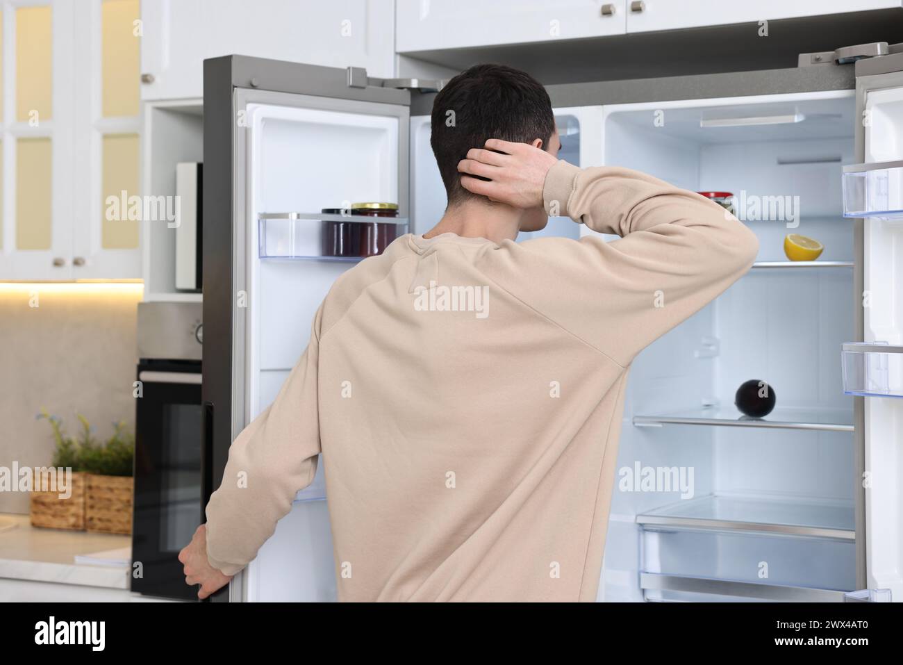 Man near empty refrigerator in kitchen at home, back view Stock Photo ...