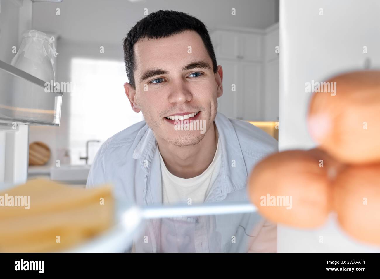 Happy man near refrigerator in kitchen, view from inside Stock Photo ...