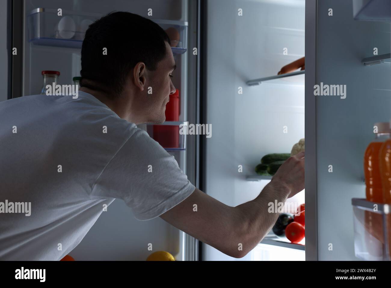 Man near refrigerator in kitchen at night Stock Photo - Alamy