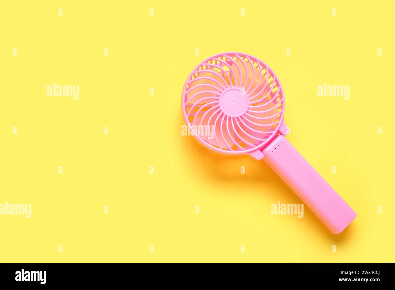 Modern manual fan on yellow background Stock Photo - Alamy
