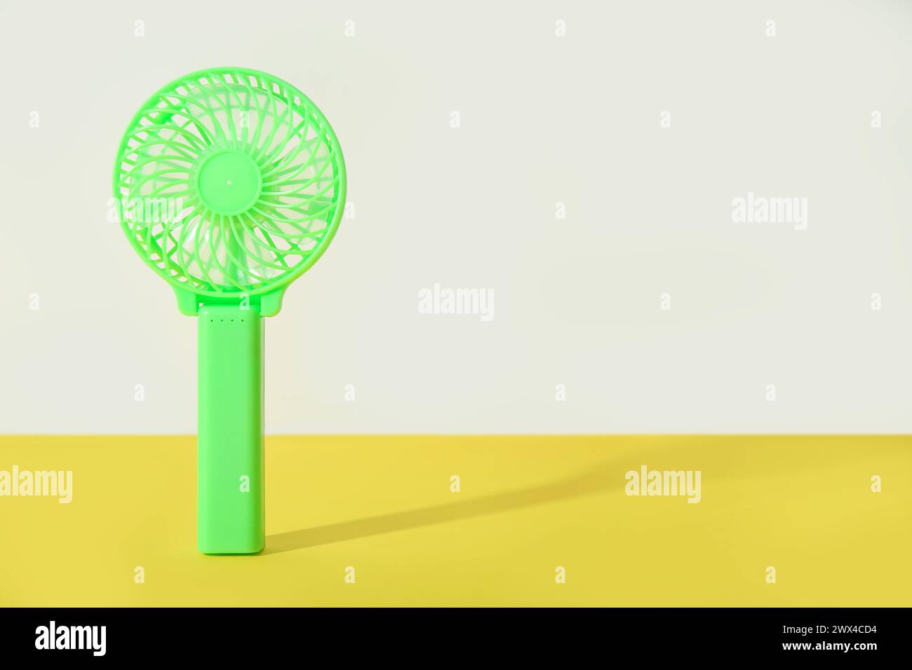 Small green electric fan on color background Stock Photo - Alamy