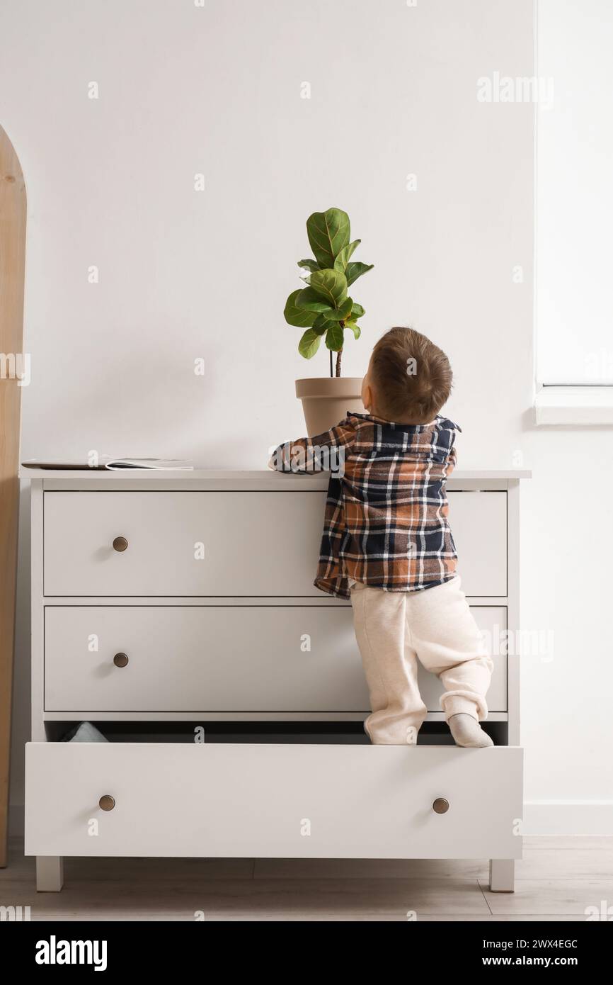 Little boy climbing on commode at home, back view. Child in danger ...