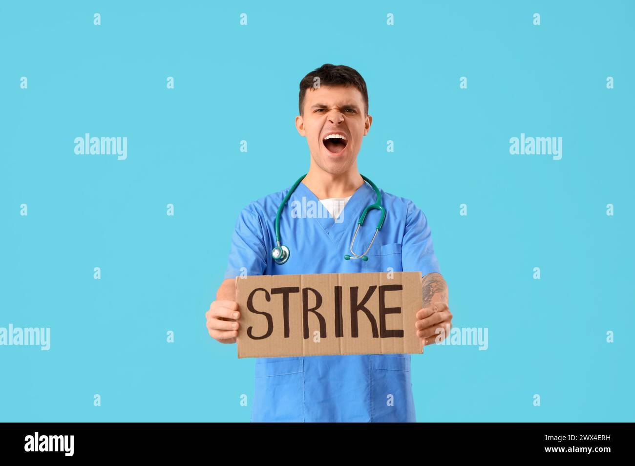 Protesting male doctor holding placard with word STRIKE on blue ...