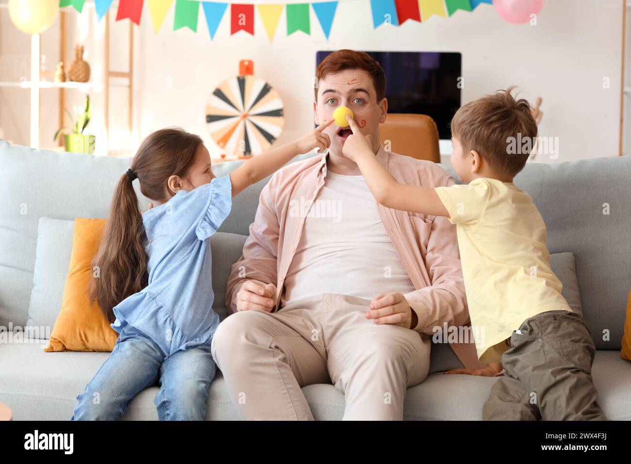 Little children pranking their father with clown nose and face ...