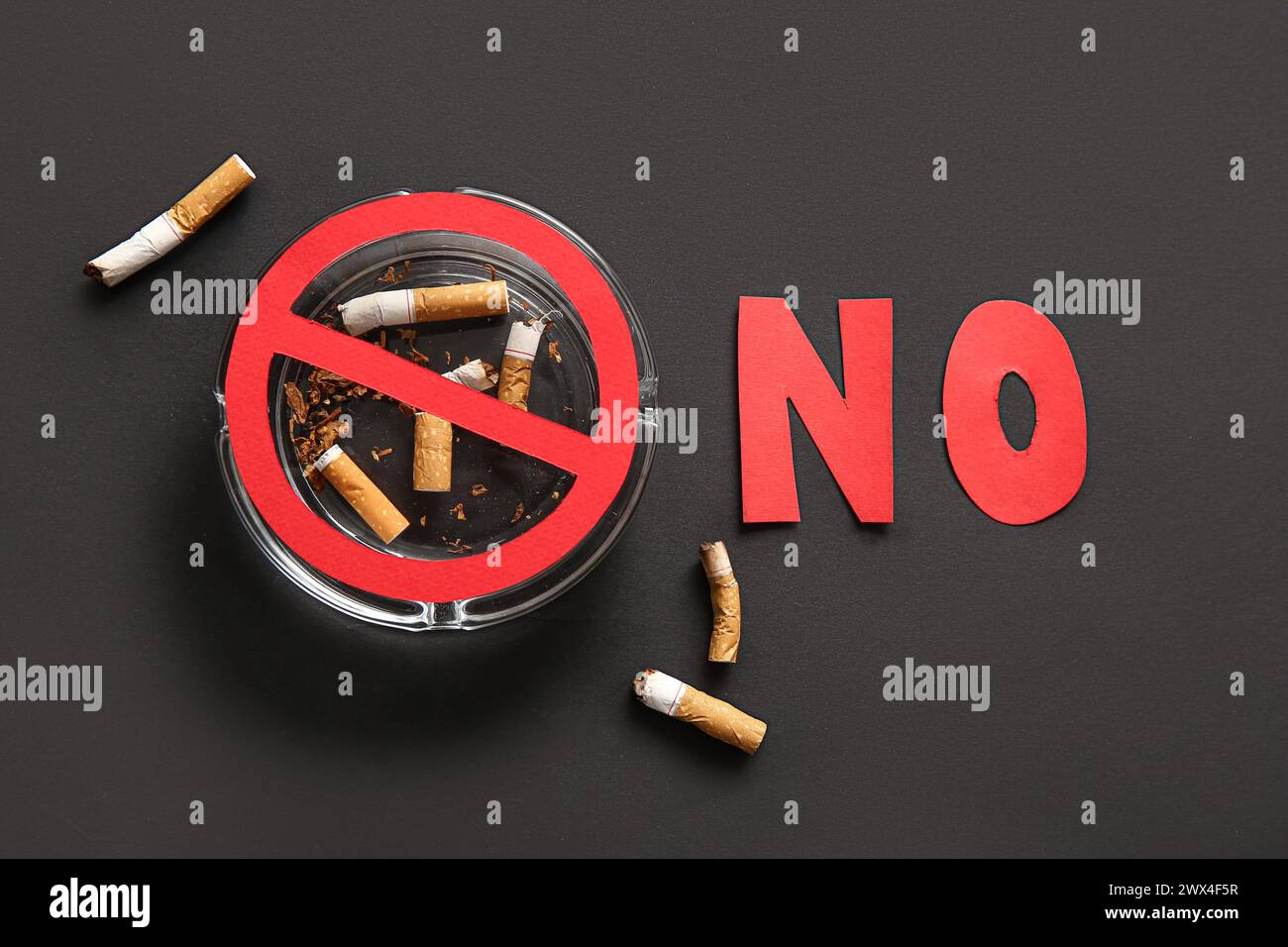 Paper word NO, stop sign, ashtray and cigarette butts on black ...