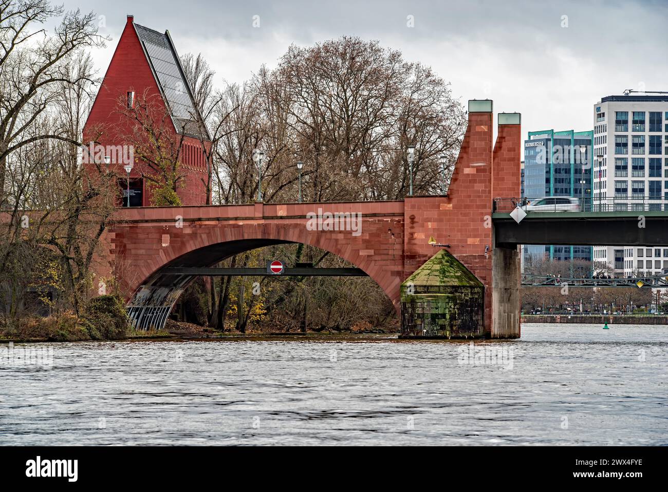 An old brick bridge spanning a river, leading into a city among ...