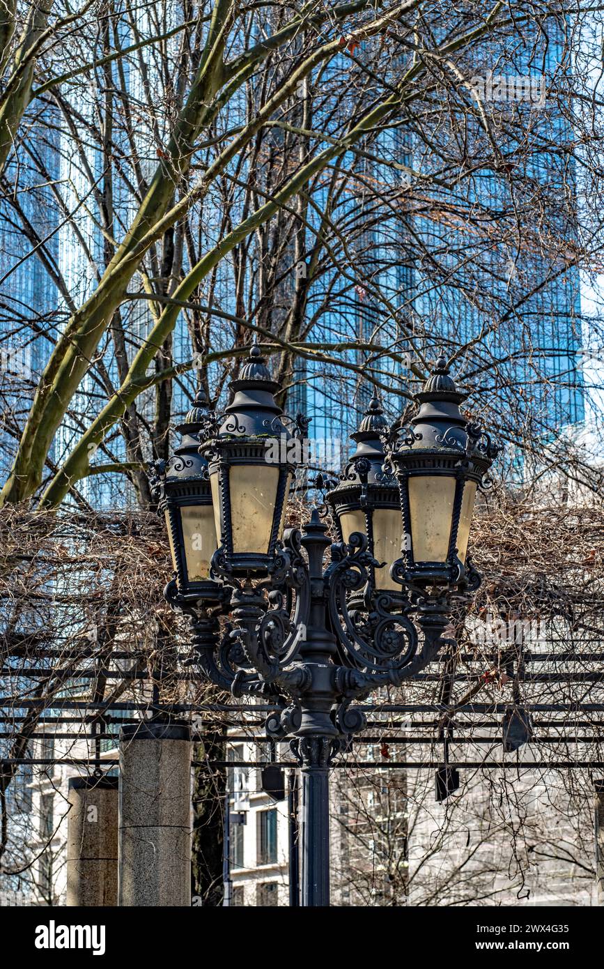 Three street lamps stand in front of a clock tower, surrounded by tall ...