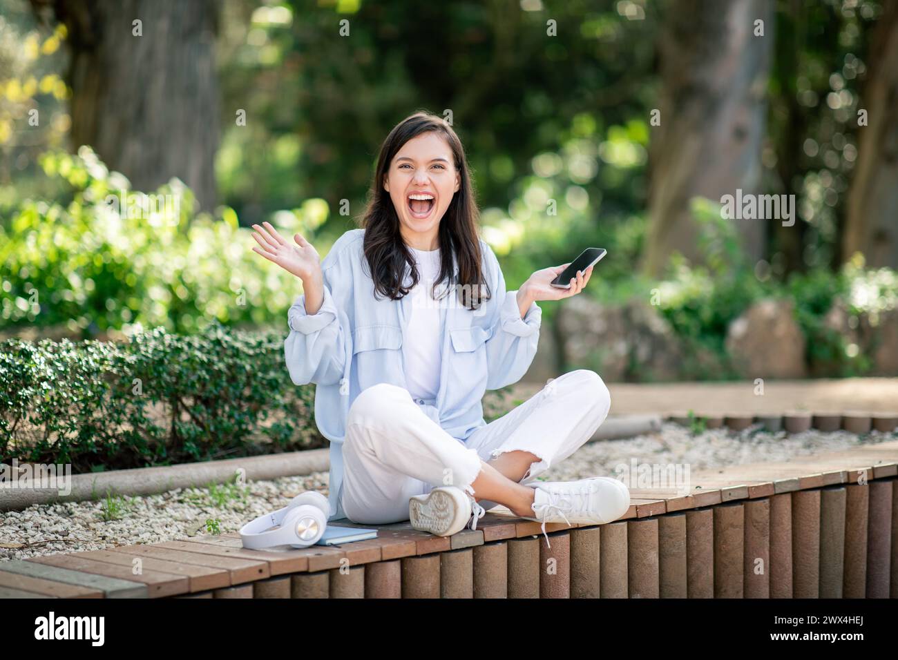 An exuberant young woman in light attire expresses joy and surprise ...