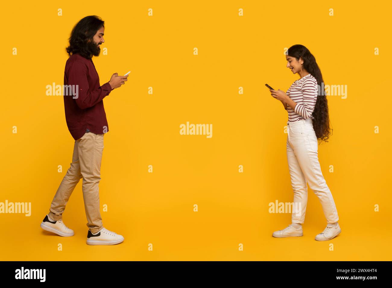 Two people standing back to back texting Stock Photo - Alamy