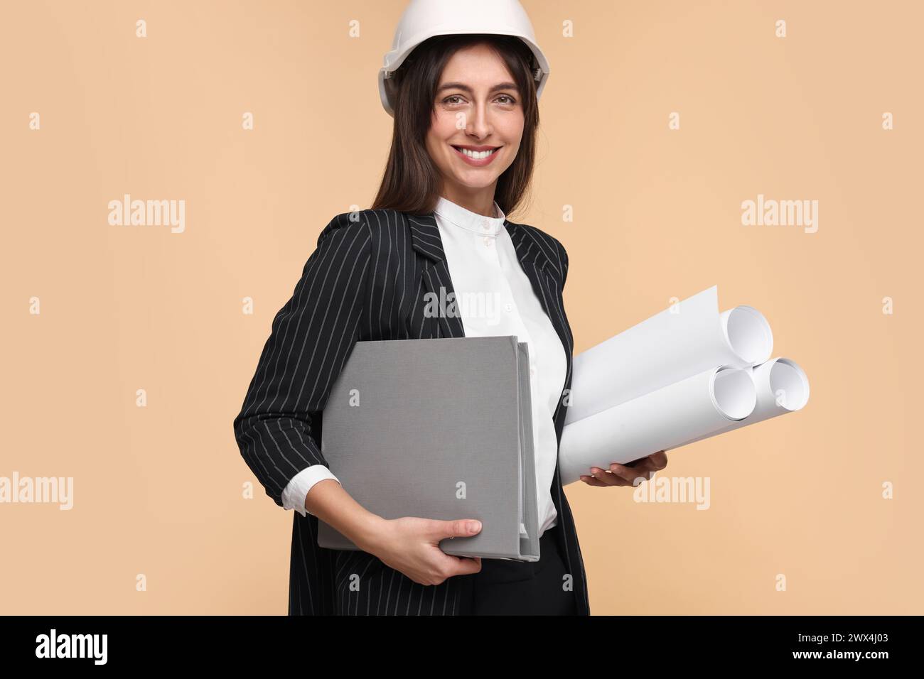 Architect in hard hat with drafts and folder on beige background Stock ...