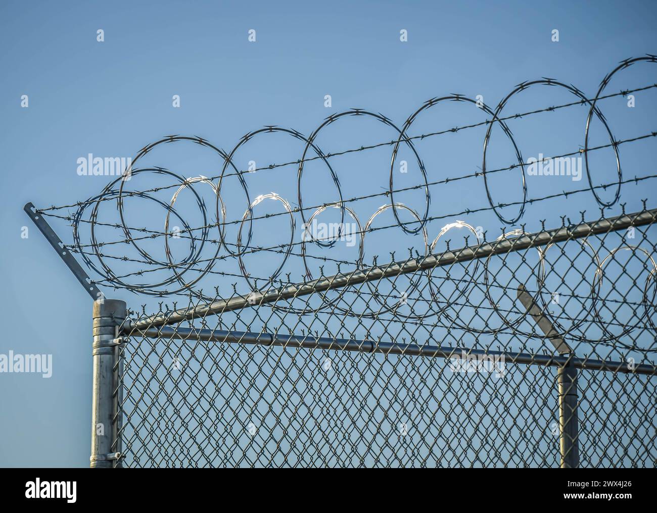 Metal fence with razor wire surrounds airport runway Stock Photo - Alamy