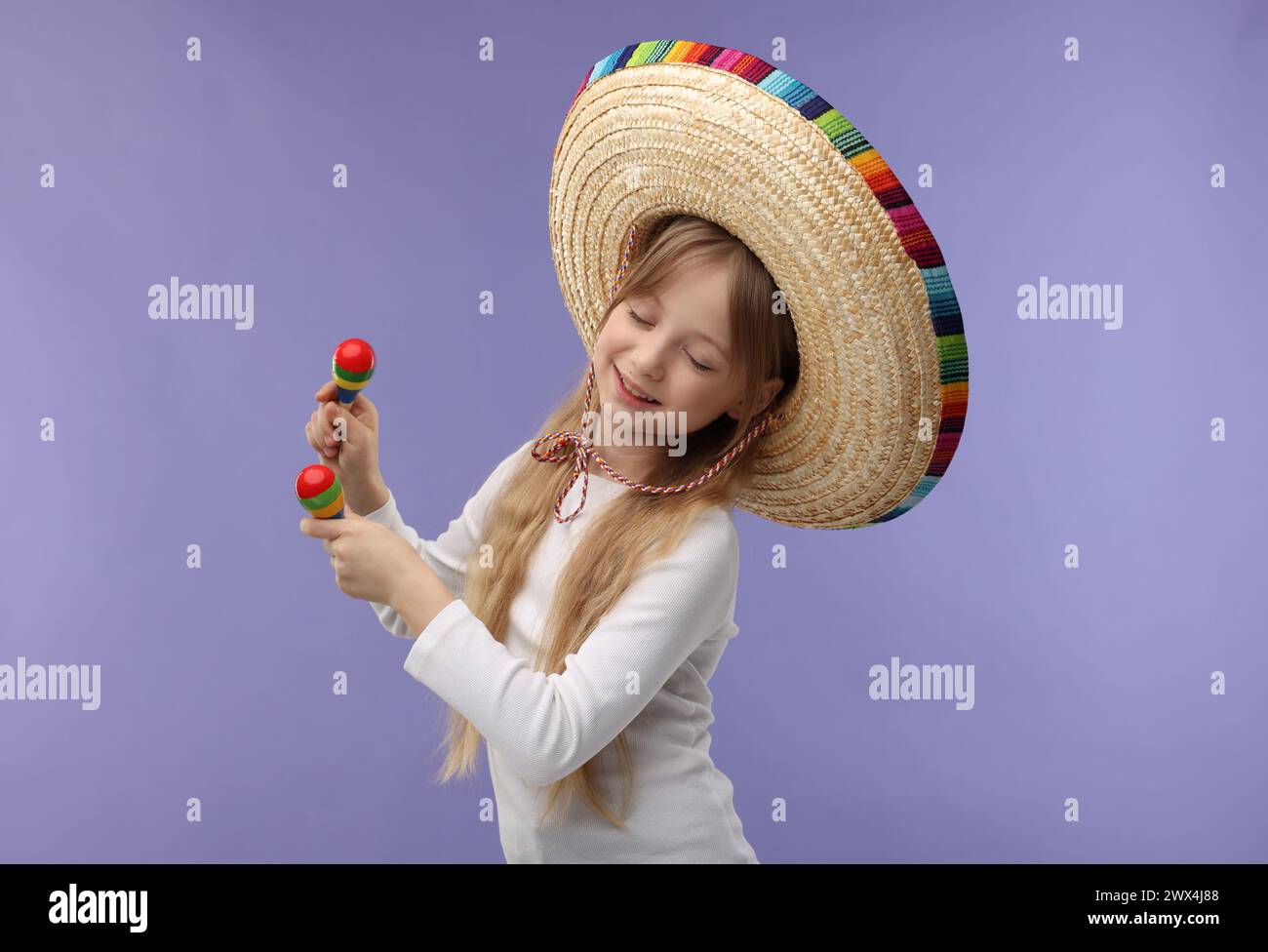 Cute girl in Mexican sombrero hat dancing with maracas on purple ...