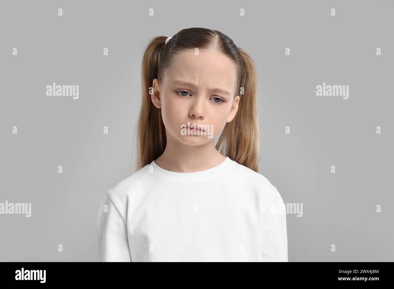 Portrait of sad girl on light grey background Stock Photo - Alamy