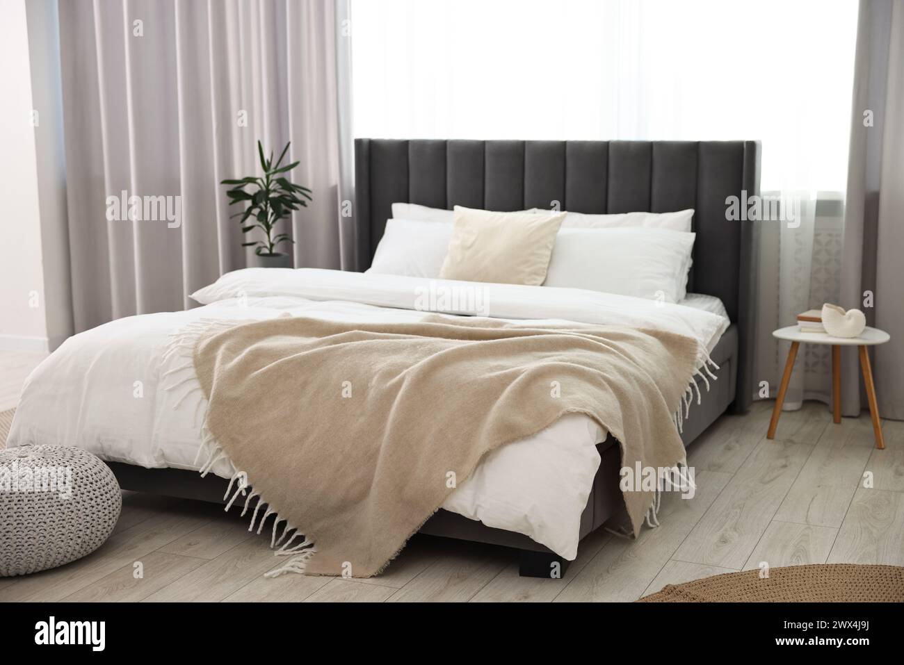 Soft beige plaid on bed in stylish bedroom. Interior design Stock Photo ...