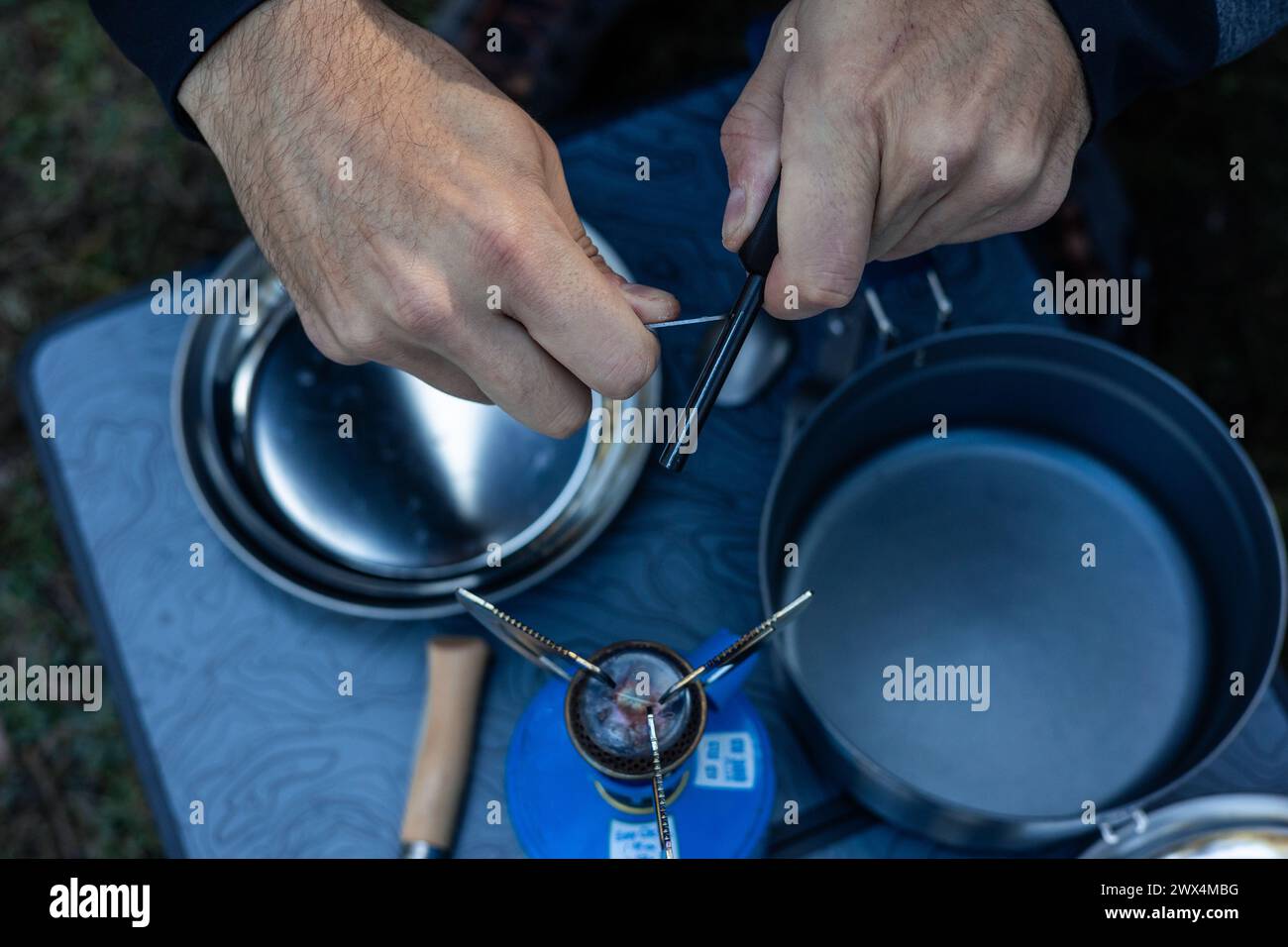 An overhead perspective captures hands igniting a camping stove using a ...