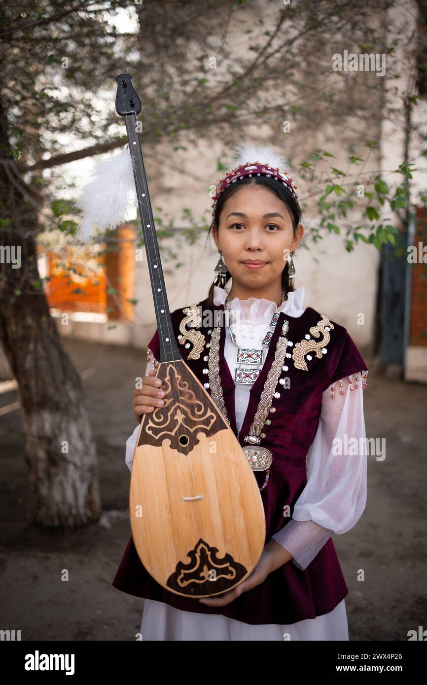A young Kazakh girl poses with a dombra, a traditional stringed ...