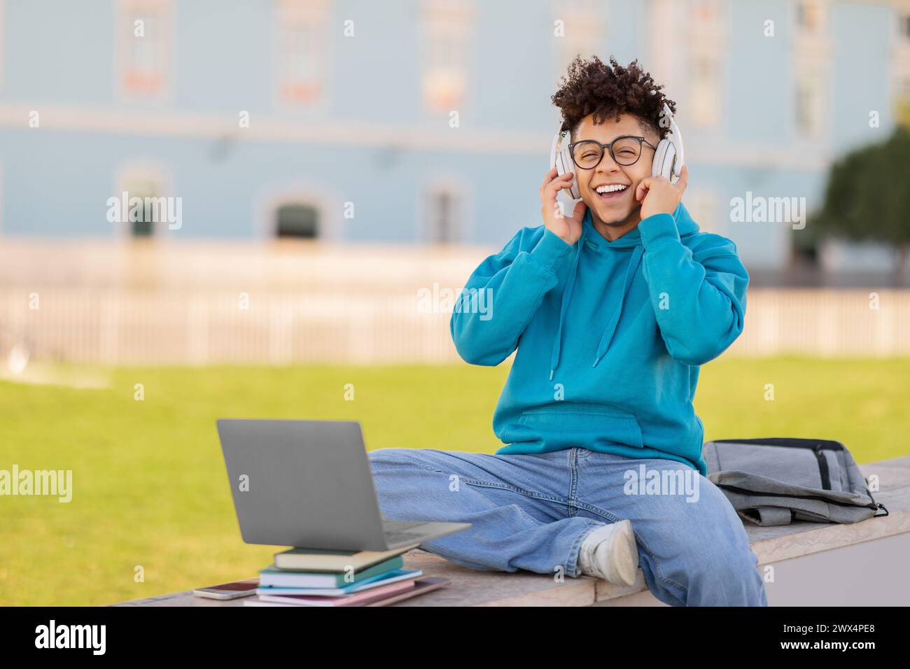 Student enjoying music while studying outside Stock Photo - Alamy