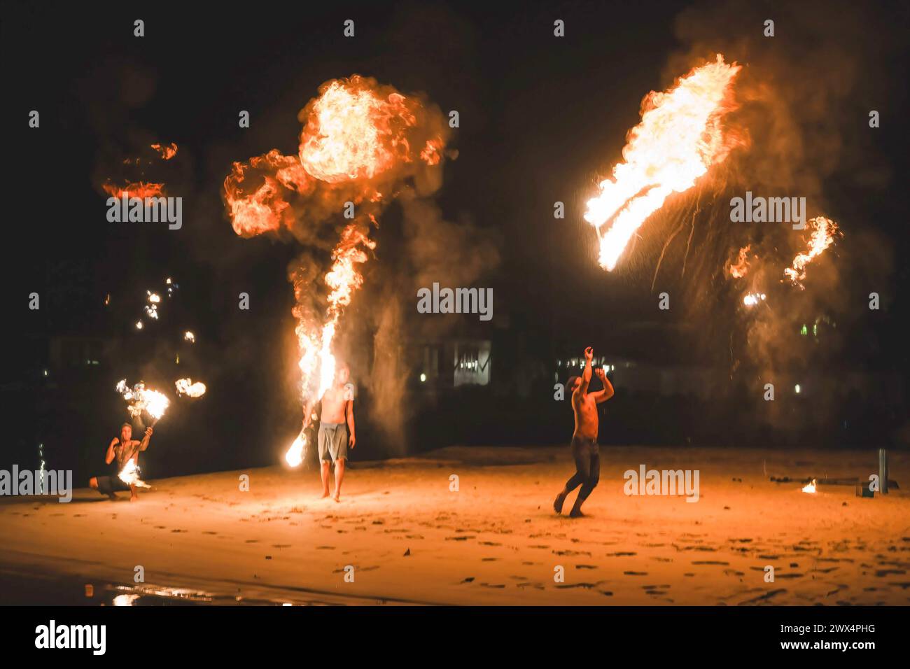 A group of fire dancers perform on a sandy part of a lagoon, on Koh ...