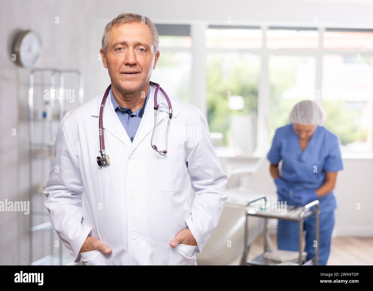 Old man doctor posing in doctor's cabinet with clinical chair Stock ...