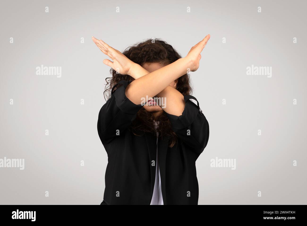 Curly haired woman with arms crossed over face Stock Photo - Alamy
