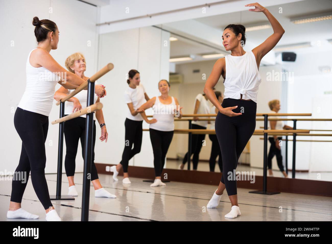 Female ballet teacher showing dancers how to dance ballet in studio ...