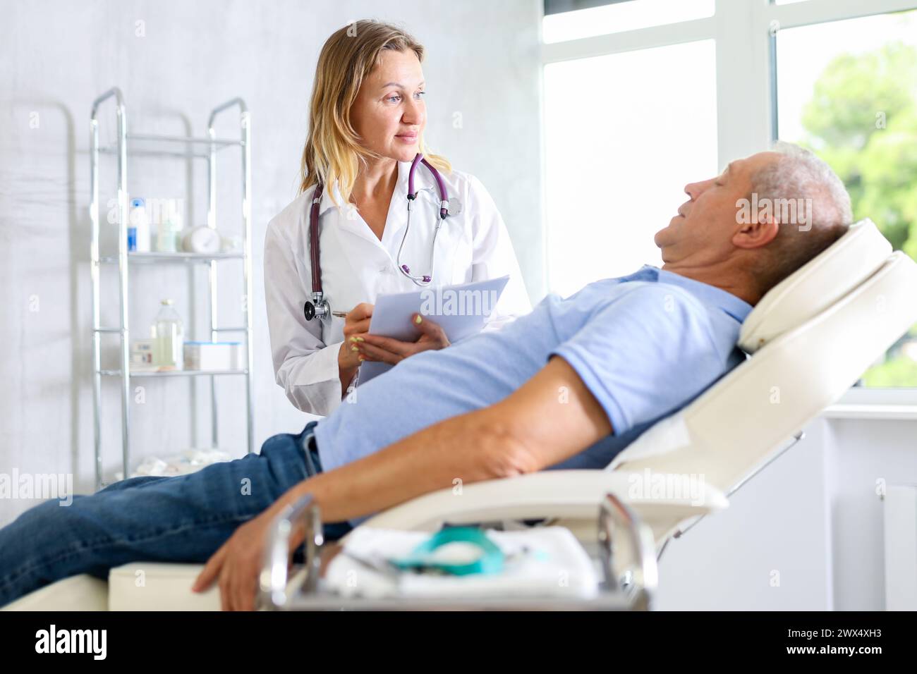Female doctor conducting questionnaire of elderly male patient in ...