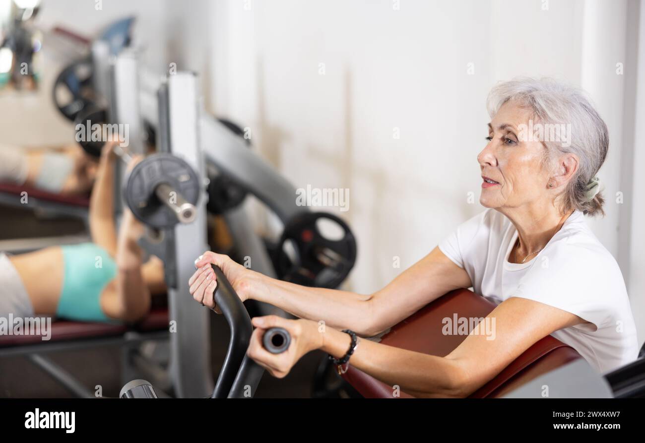 Elderly woman trains her arm muscles on machine Stock Photo - Alamy