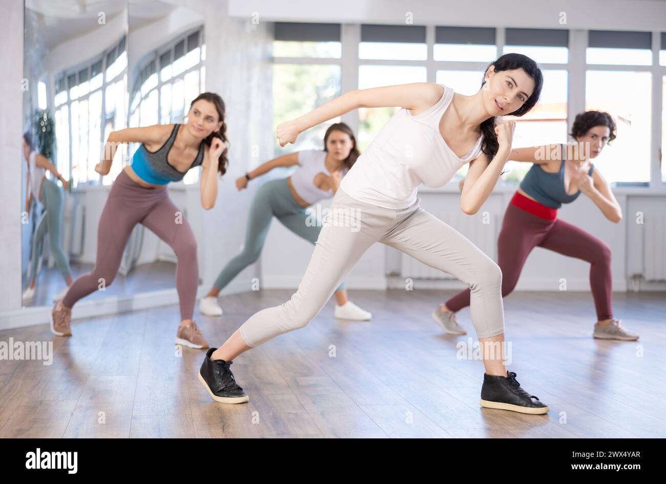 Young female teacher conducts modern dance lessons for group of girls ...