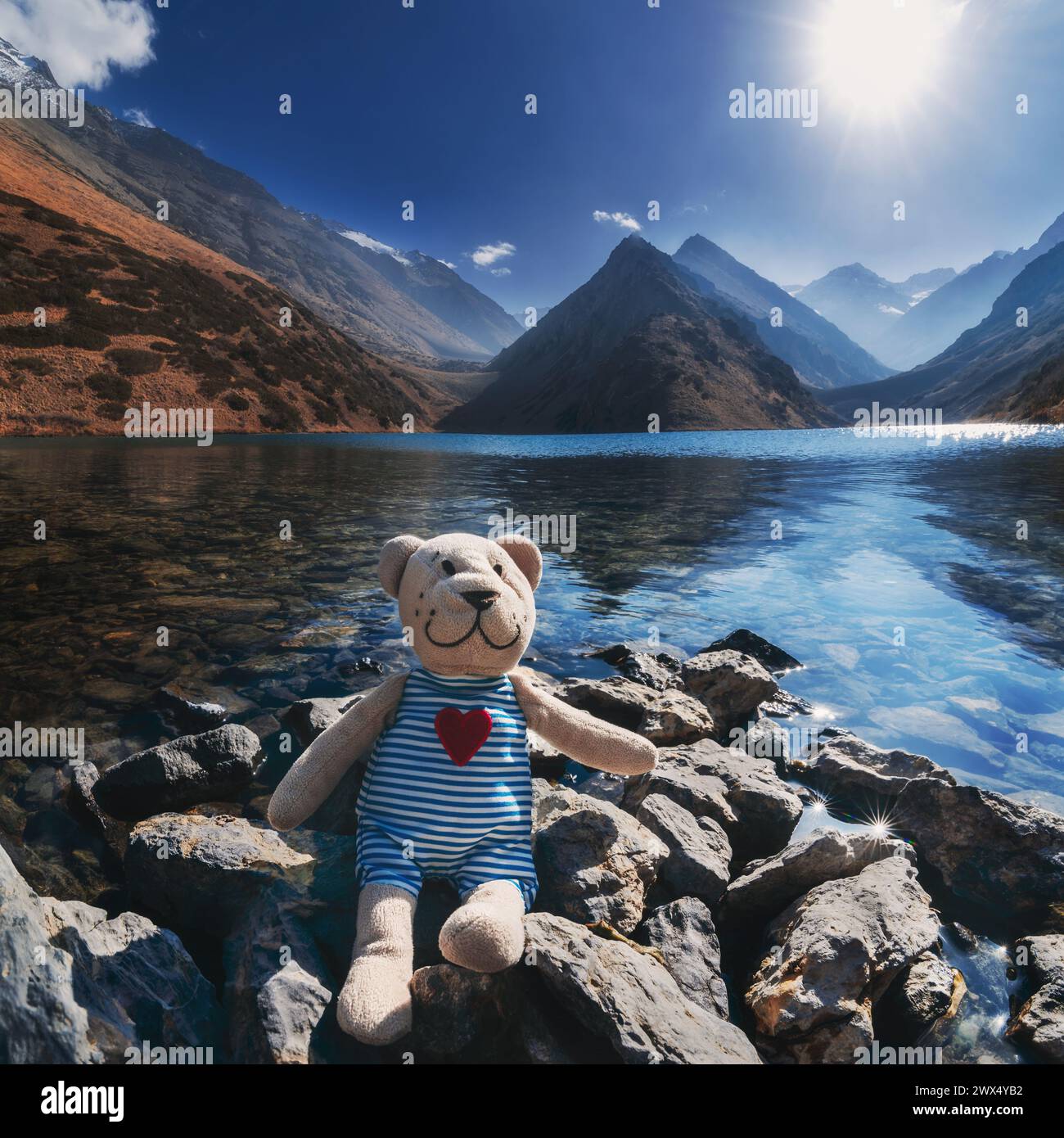 toy plush teddy bear sits relax on rocks near Koksay Lake in Kazakhstan ...