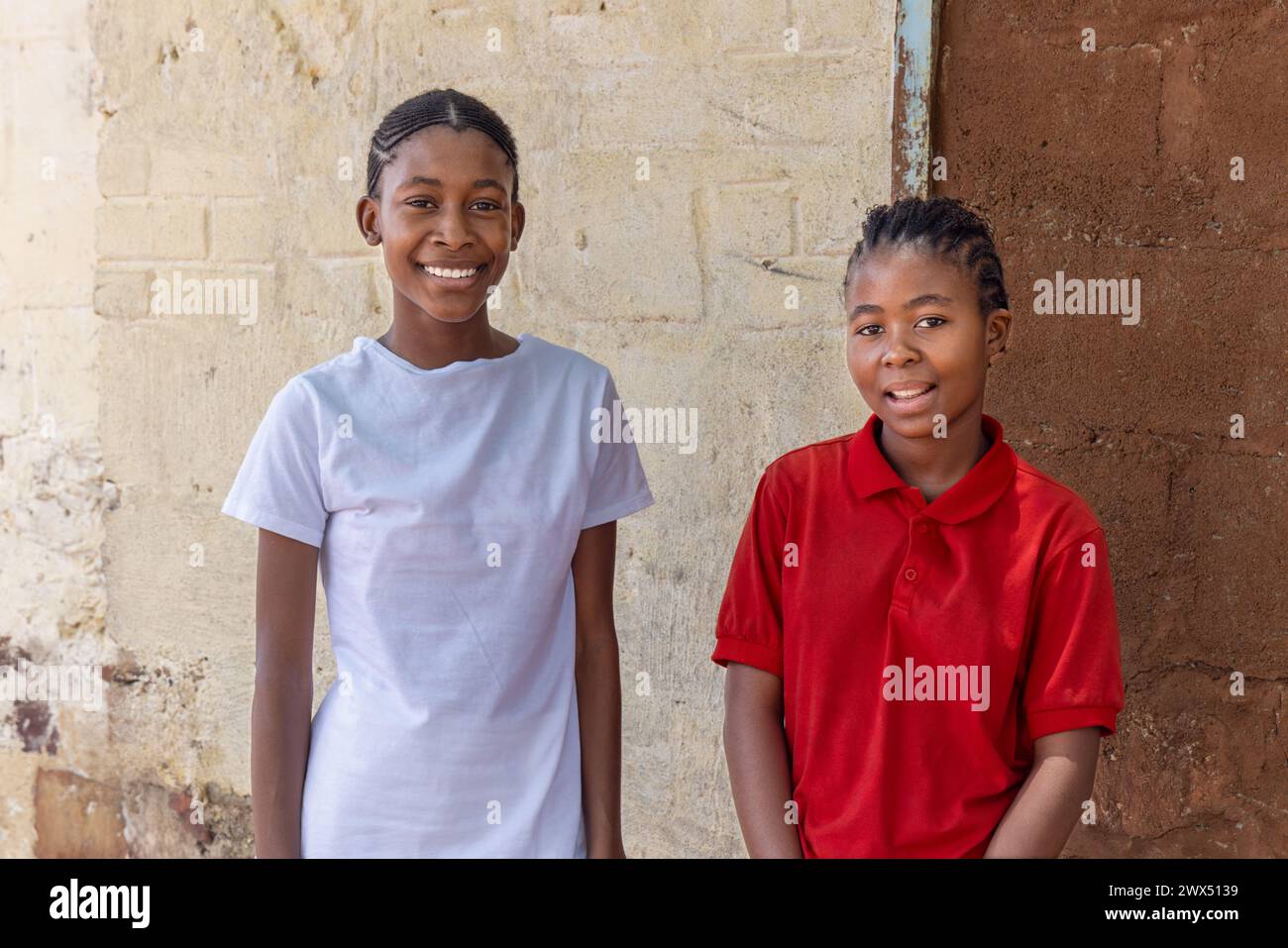 portrait of two african villager girls with braids standing outdoors in ...