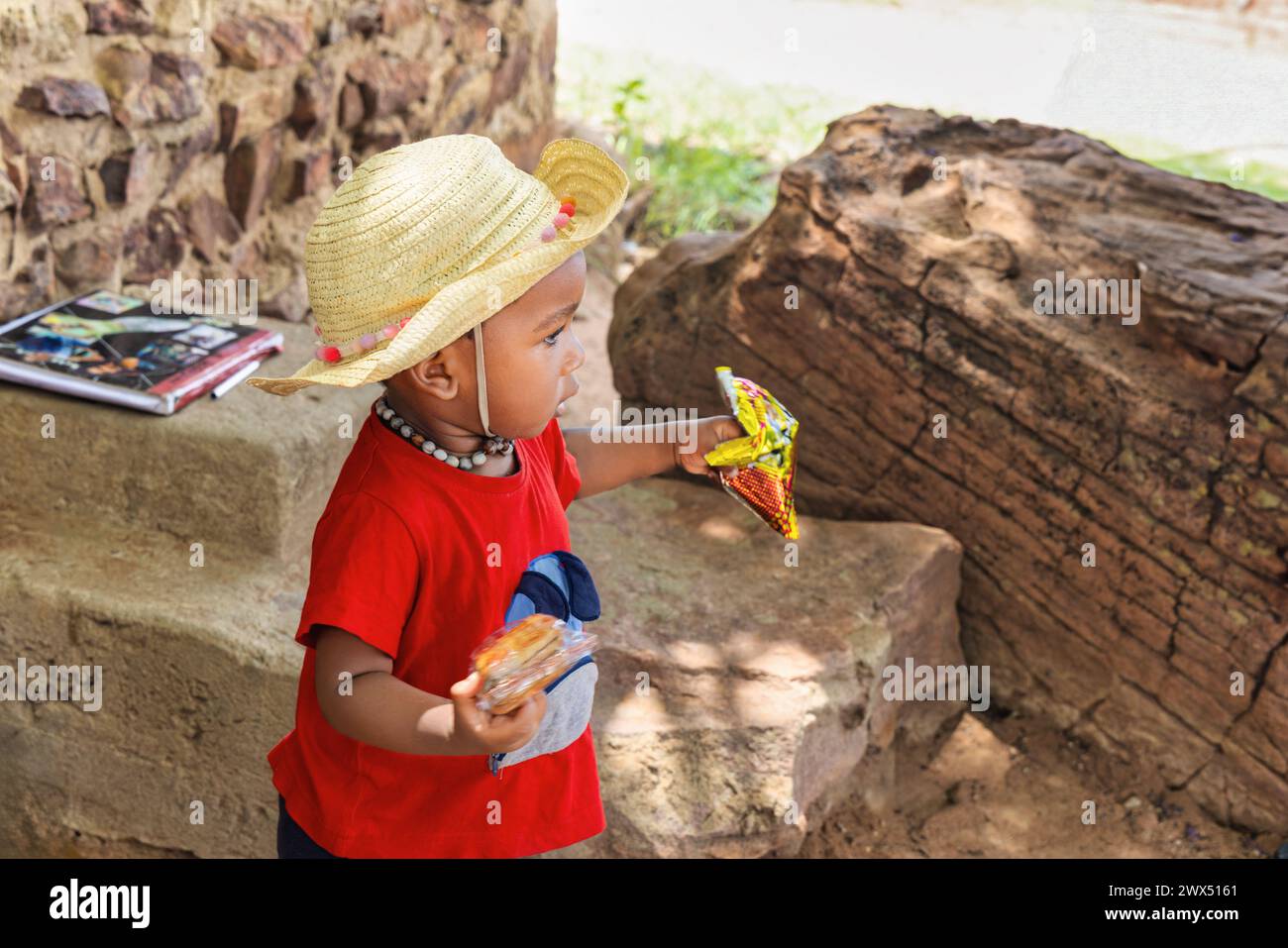 portrait of african child villager eating some snacks, in the yard in ...