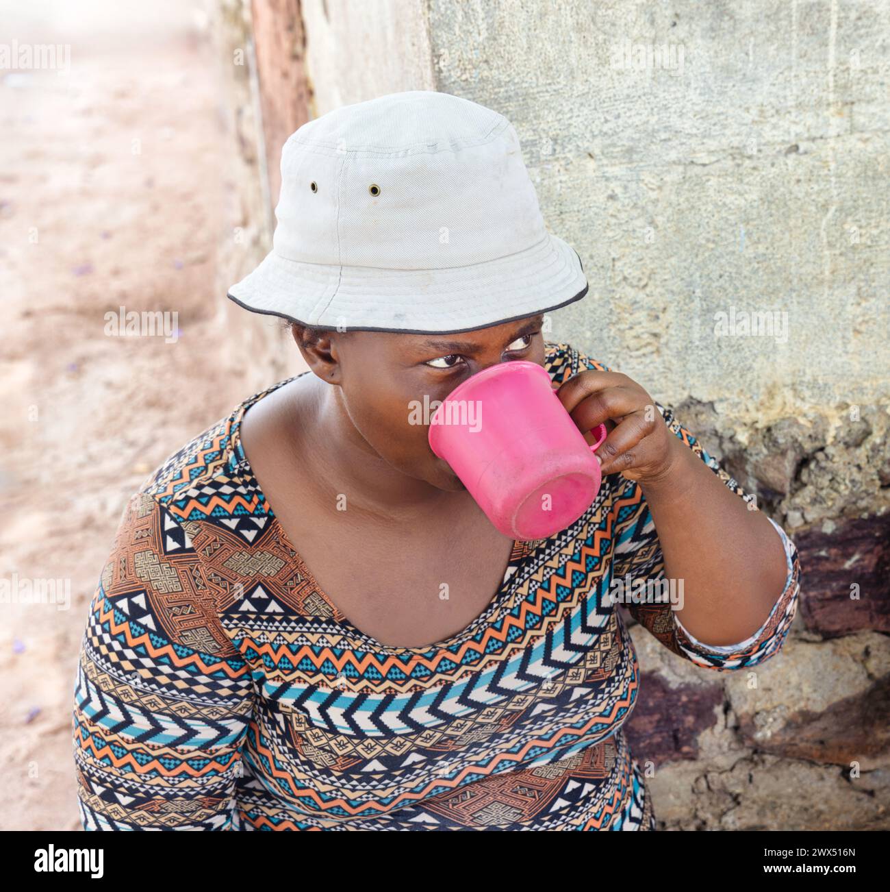 Portrait Of African Woman Thirsty Villager Drinking Water In The Yard In Front Of The House