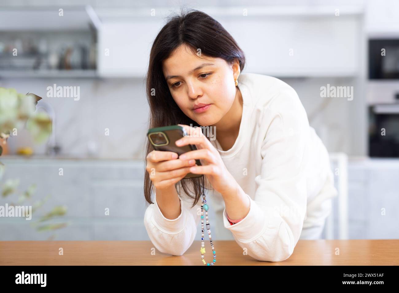 Young woman scrolling through social media on smartphone at home Stock ...
