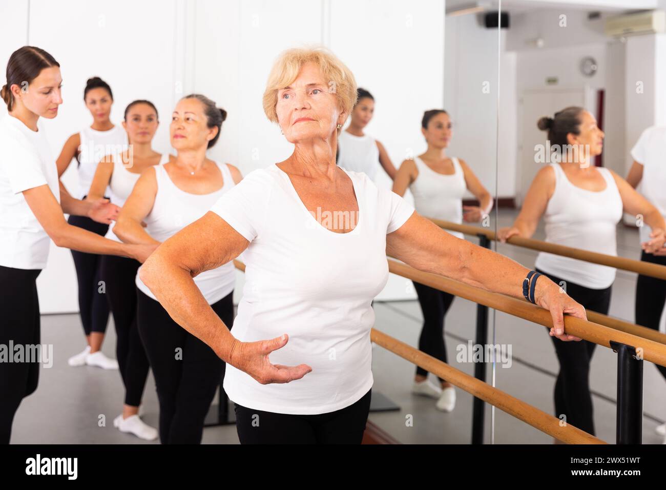 Dancing women stand in a ballet stance, where the choreographer helps ...