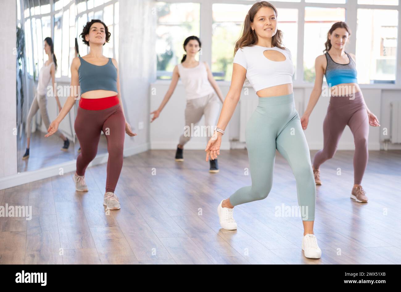 Young female teacher conducts modern dance lessons for group of girls ...