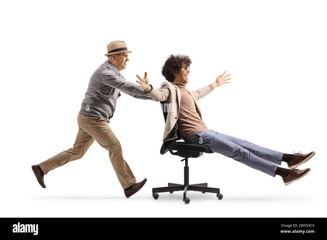 Elderly man running and pushing young man seated in an office chair ...