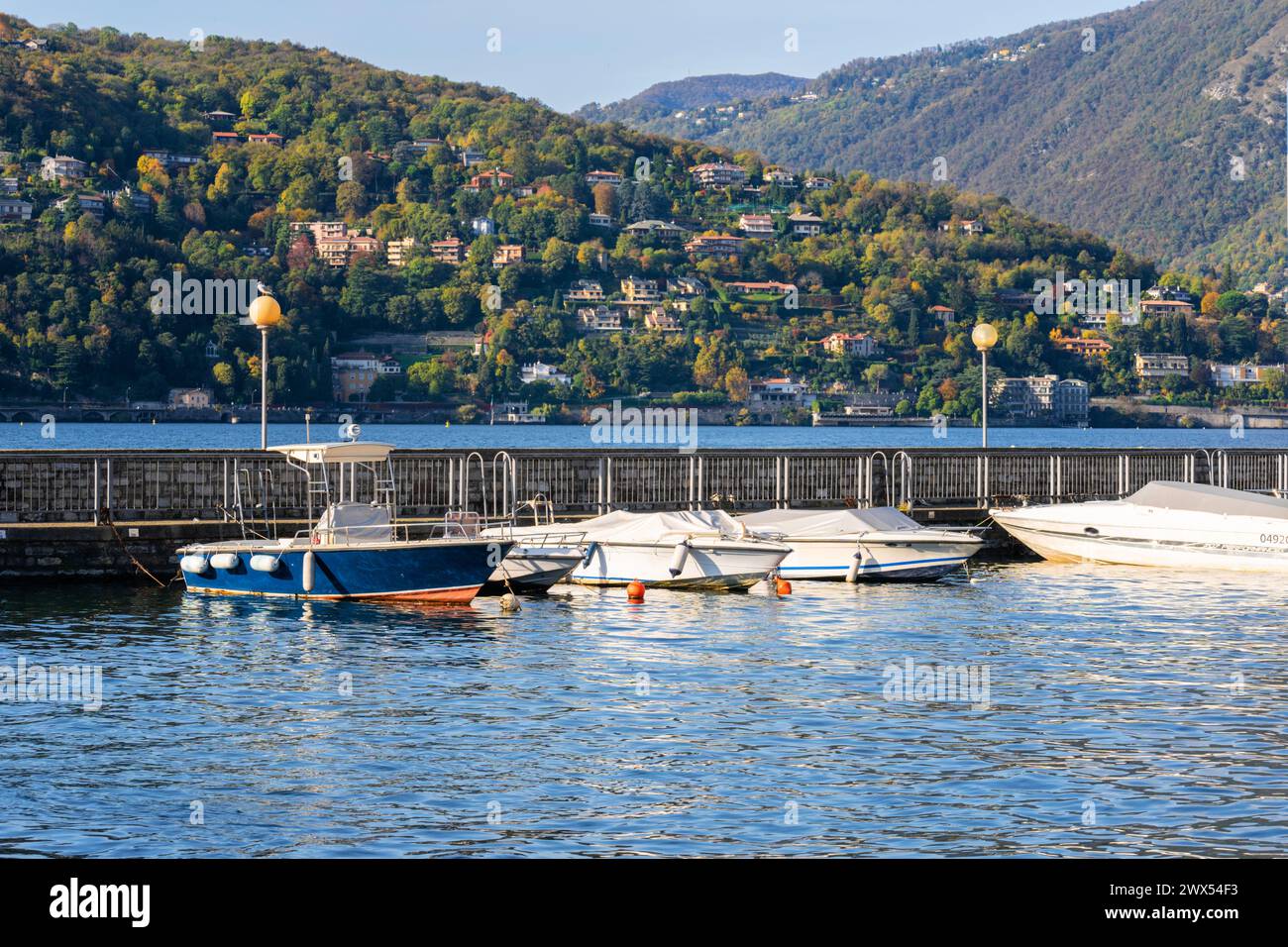 Pier and boats docked at marina on Lake Como in the harbor of the city ...