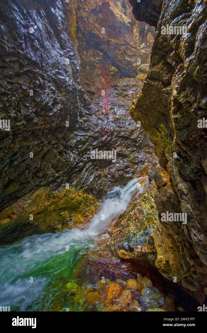 Churning water rushes through a rugged gorge, the narrow canyon walls ...