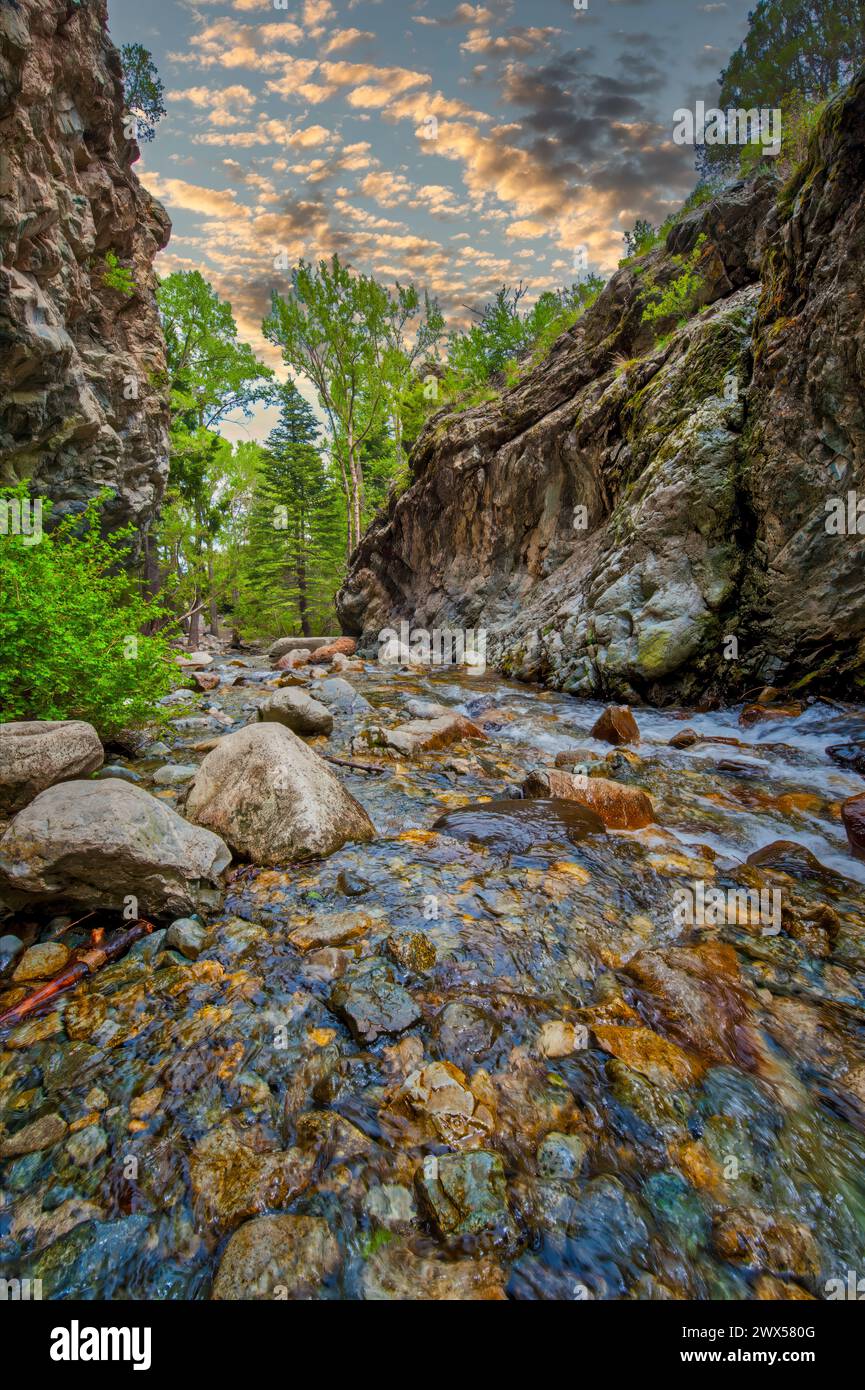 Breathtaking sunset sky with light clouds above a stream with rocky ...